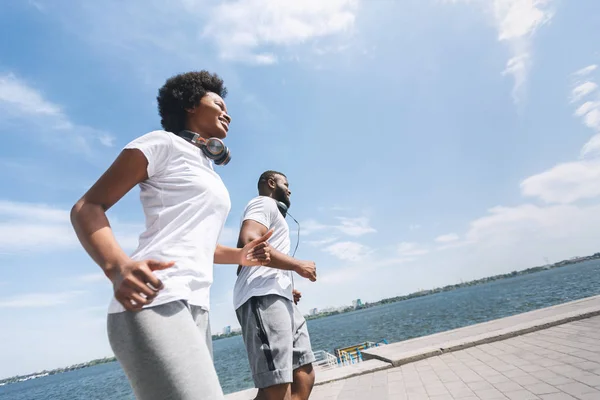 Cheerful African American Couple Jogging Along River Embankment In City ...