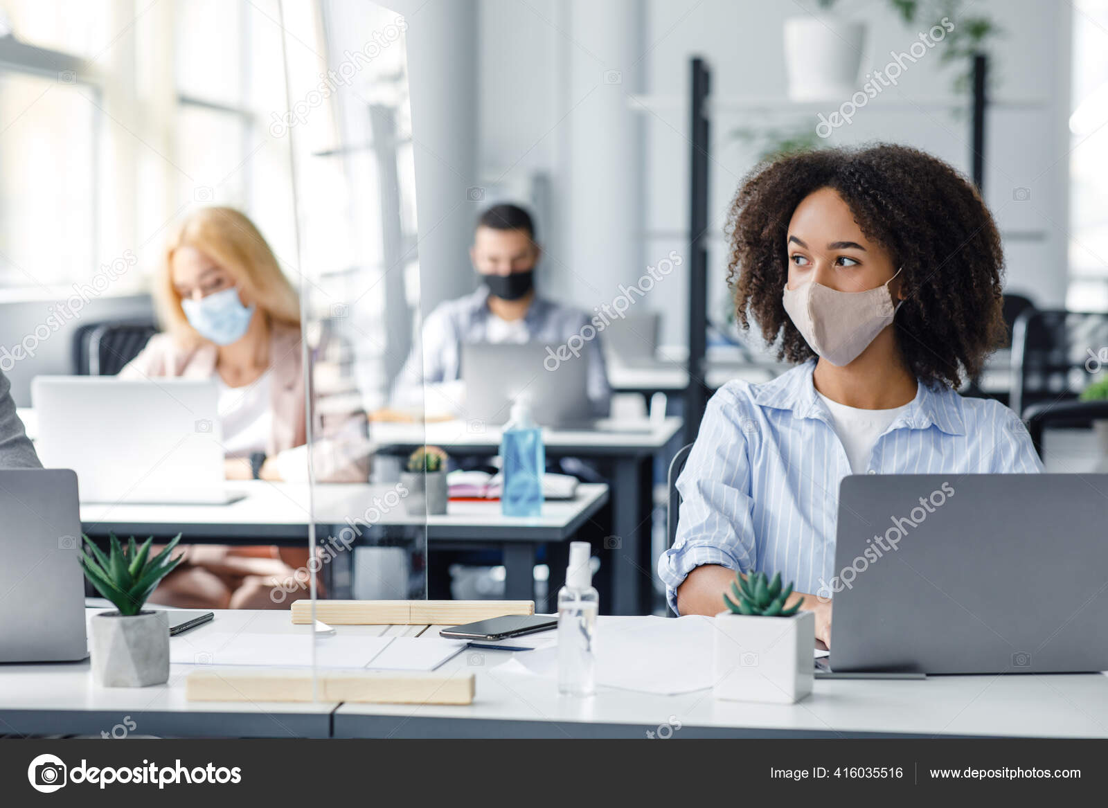 Work on project in corporate company after lockdown. African american woman in mask creating ...