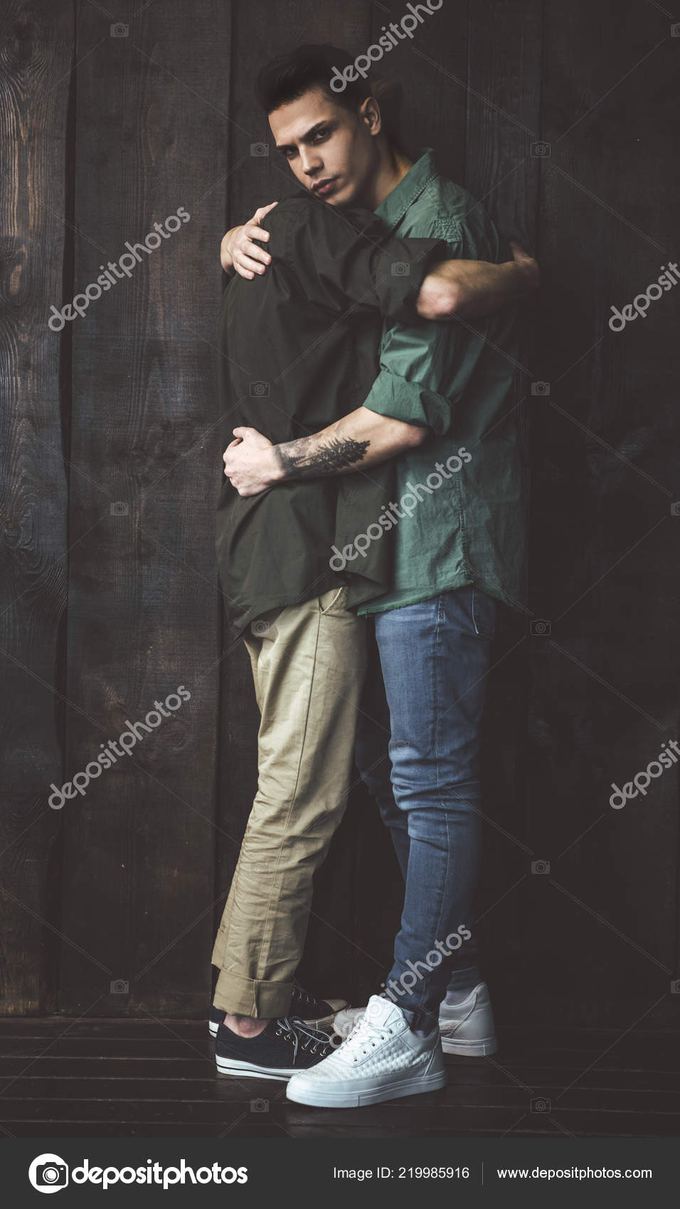 Gay couple hugging while standing against the wall Stock Photo by ...