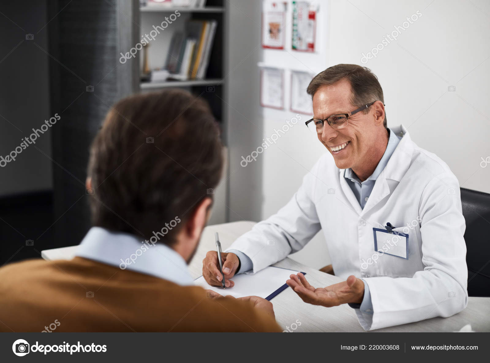 Smiling doctor talking with patient in office Stock Photo by ...