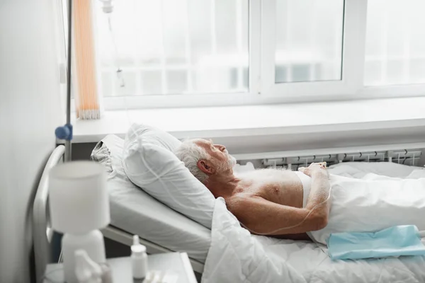 Senior man in hospital bed — Stock Photo © ArturVerkhovetskiy #140179506