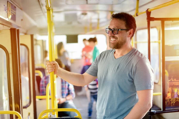 Happy middle age man holding for a bar in a bus and smiling. Waiting ...