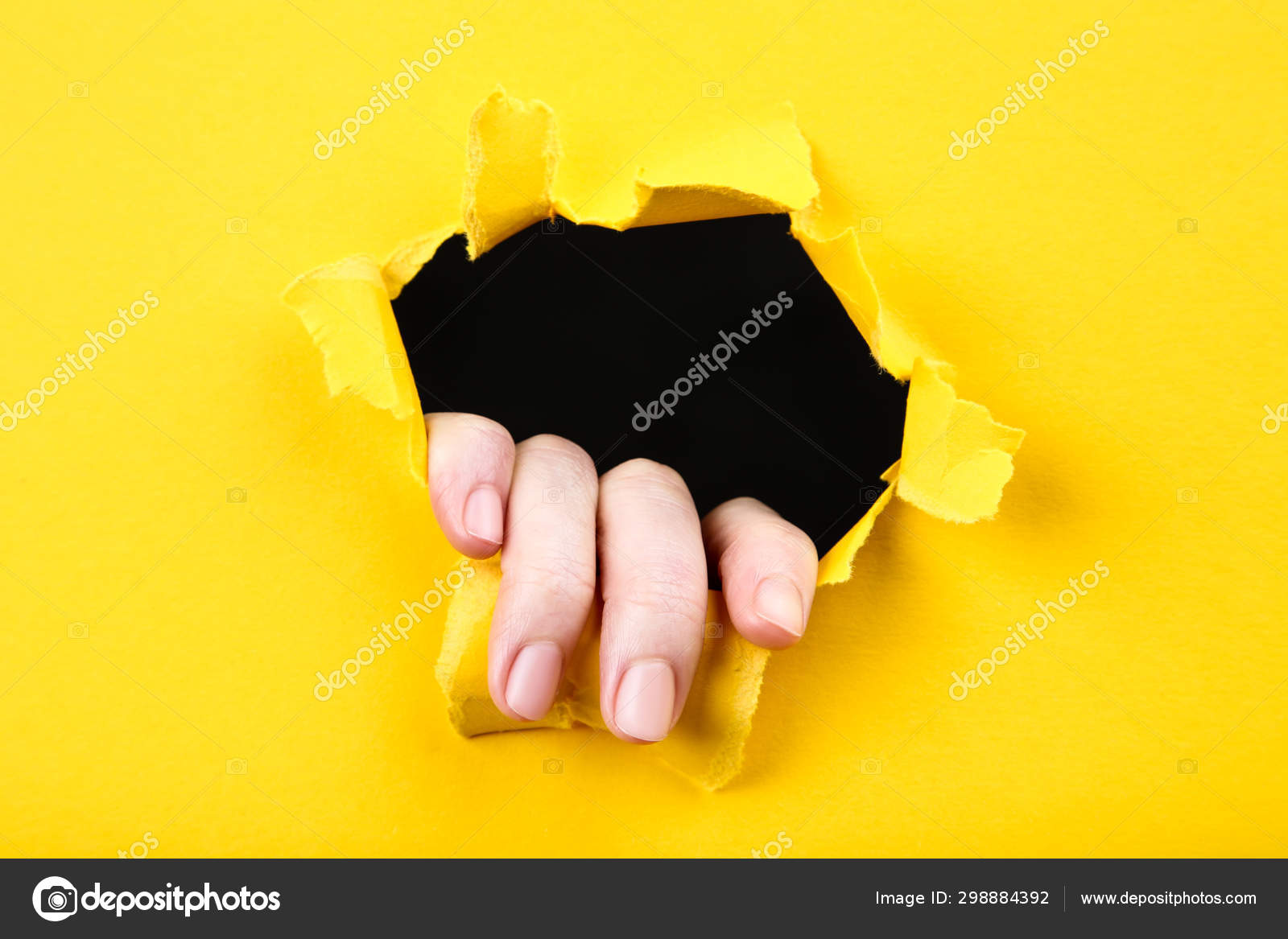 Hand tearing hole in yellow paper Stock Photo by ©5seconds 298884392