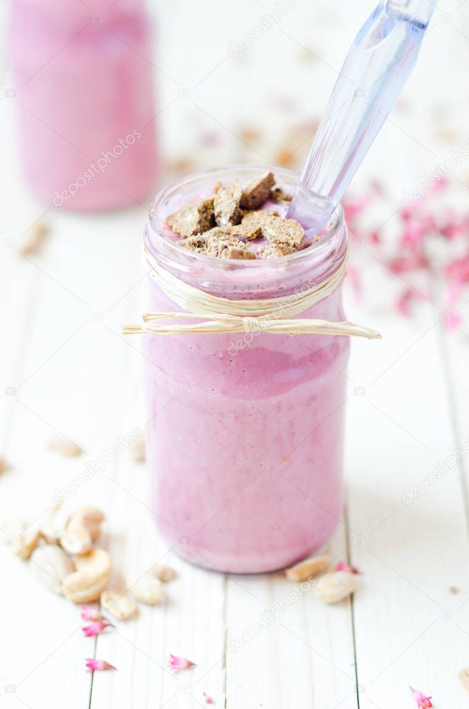 Smoothie de fresa rosa en tarro retro con flores moradas y nueces ...