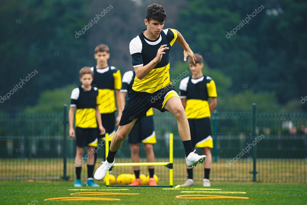 Joven futbolista en entrenamiento saltando sobre obstáculos. Campamento ...