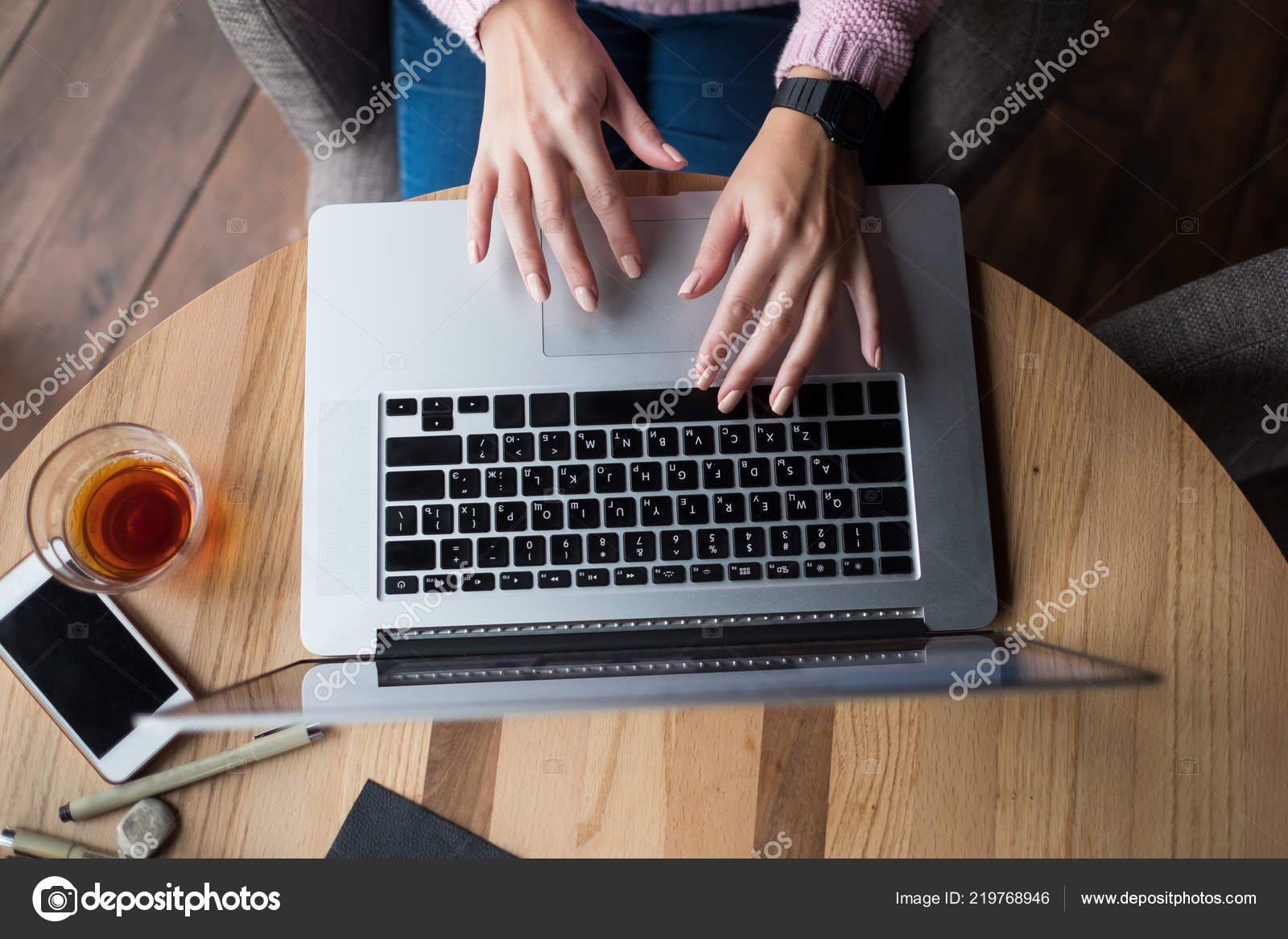 Woman is working by using a laptop computer on wooden table. Hands ...
