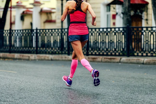female runner in pink compression calf sleeves running marathon under ...