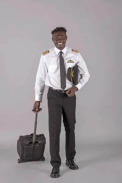 A young airline pilot with an african dred hairstyle and flight bag on ...