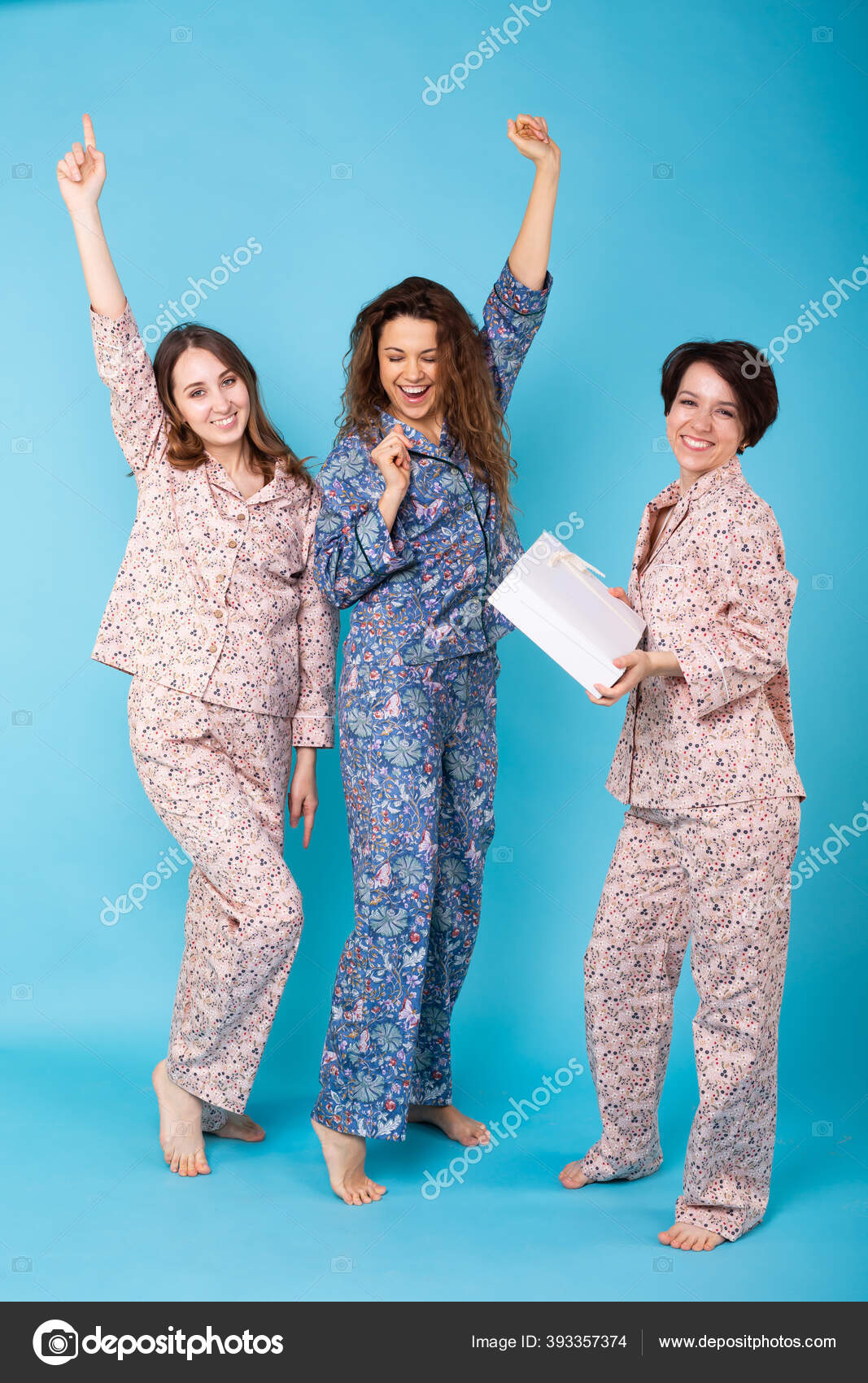 Portrait of three beautiful young girls wearing colorful pyjamas having ...