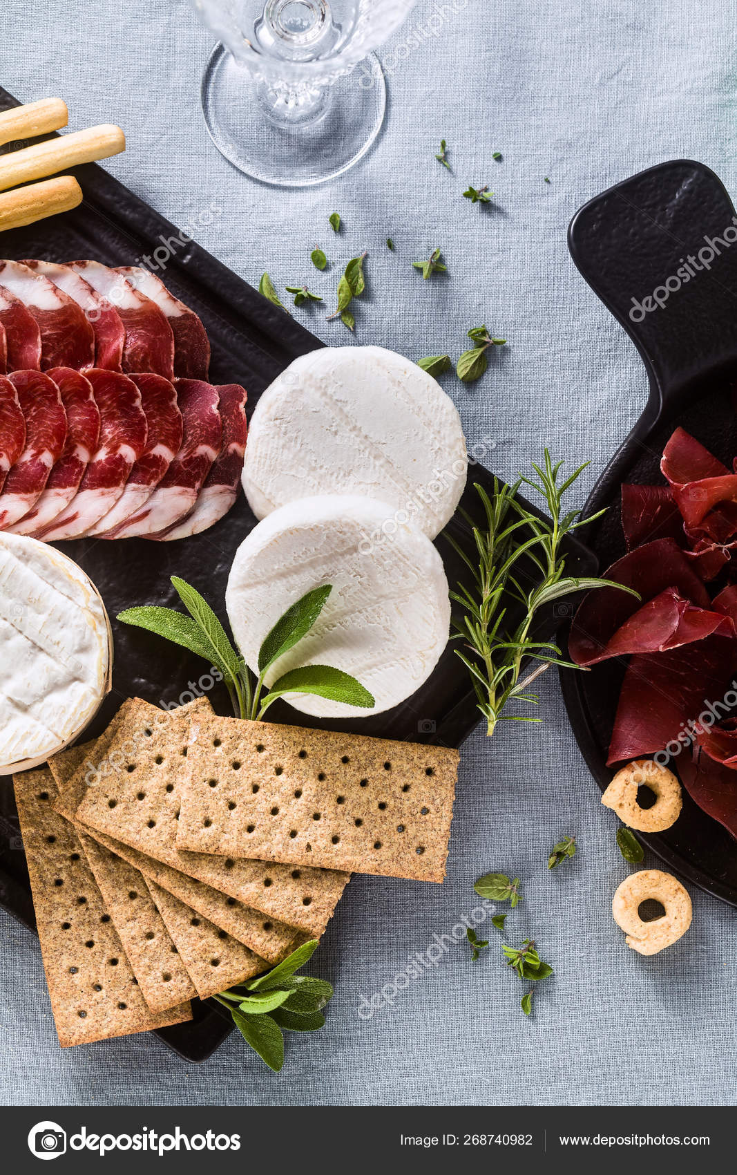 Cold cuts and cheese are served on a tray on a table with white Stock ...