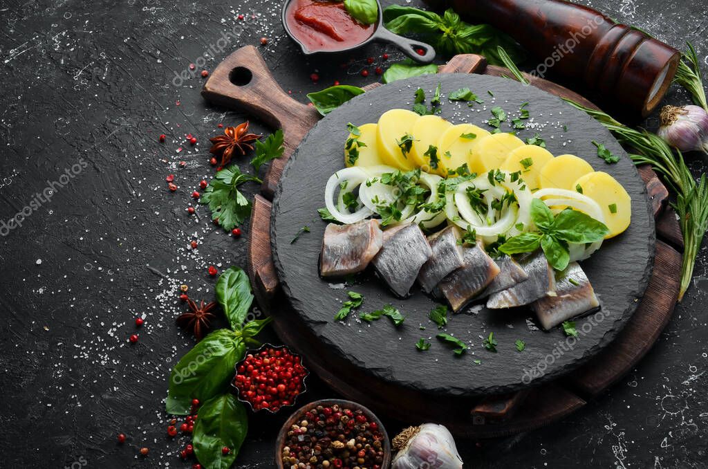Comida. Arenque con cebolla y patatas en un plato de piedra negra ...
