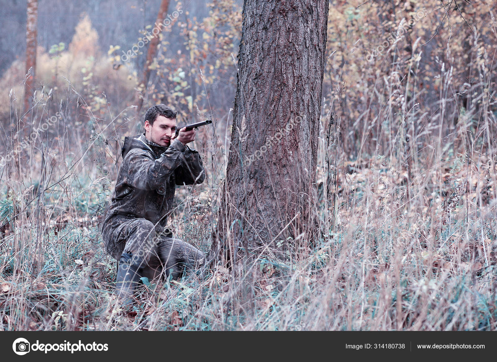 A man in camouflage and with a hunting rifle in a forest on a sp ...