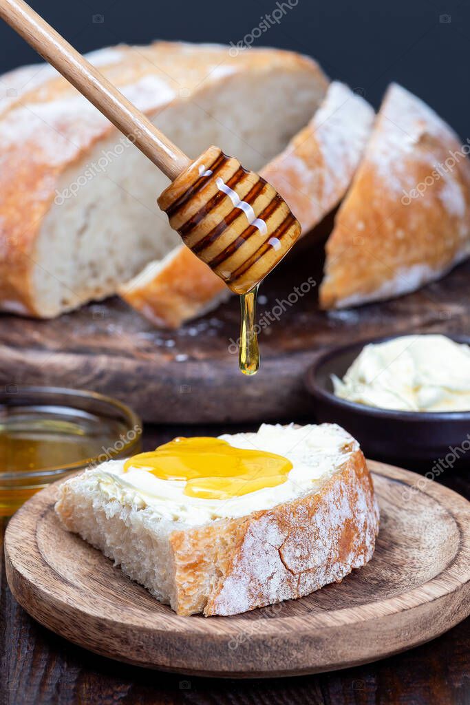 Trozo de pan Classic Boule fresco con mantequilla y miel en un plato de ...