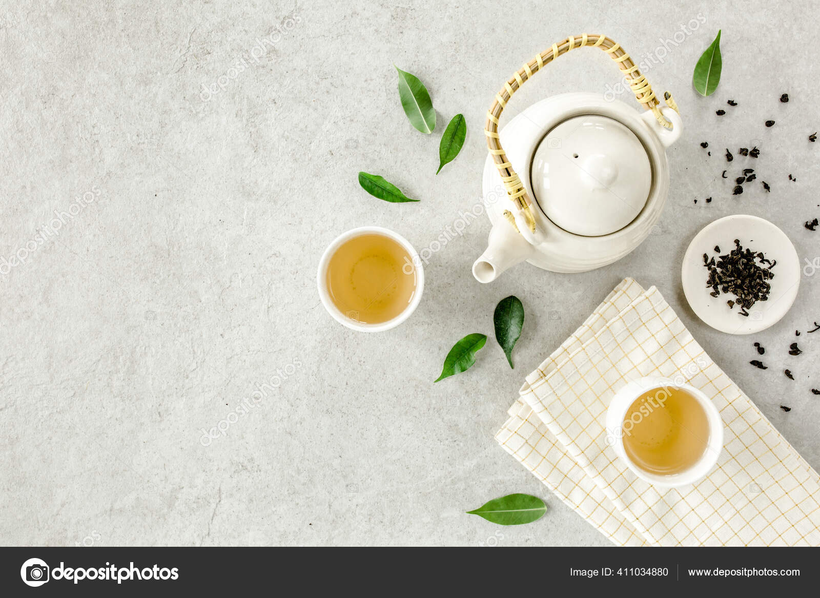 Herbal tea with two white tea cups and teapot, with green tea leaves ...