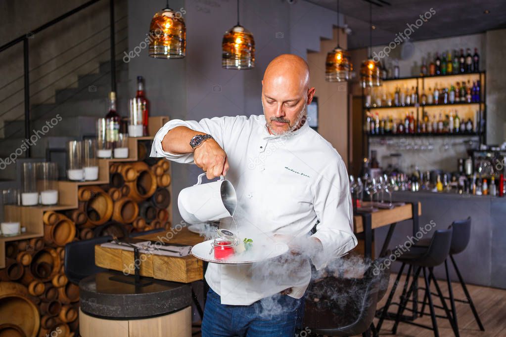 Hombre italiano guapo calvo con una barba en uniforme blanco chef en un ...