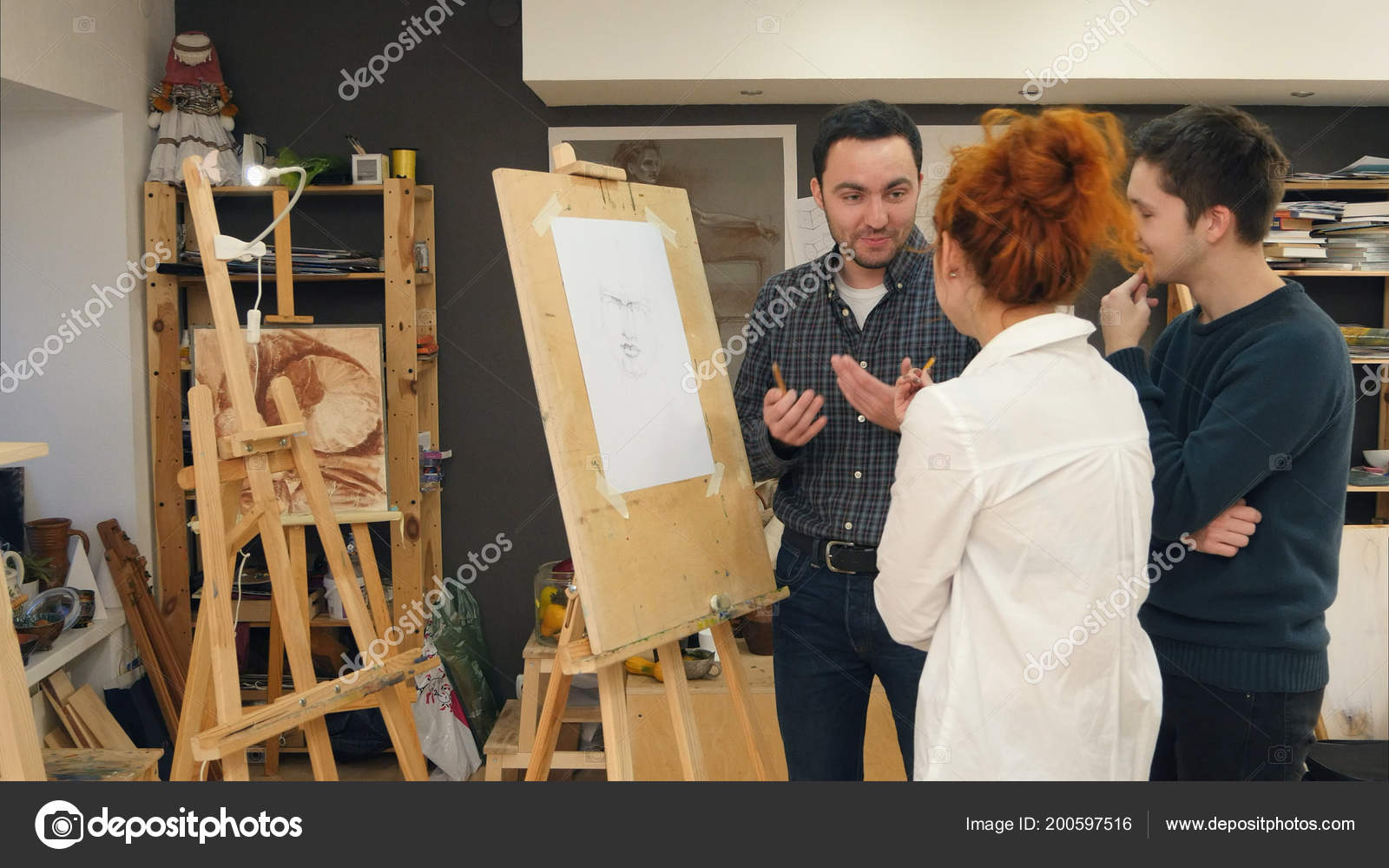 Three cheerful art students discussing painting in studio Stock Photo ...