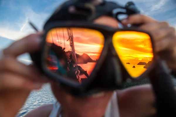 A dive mask reflects a brilliant sunset in Raja Ampat, Indonesia. This ...