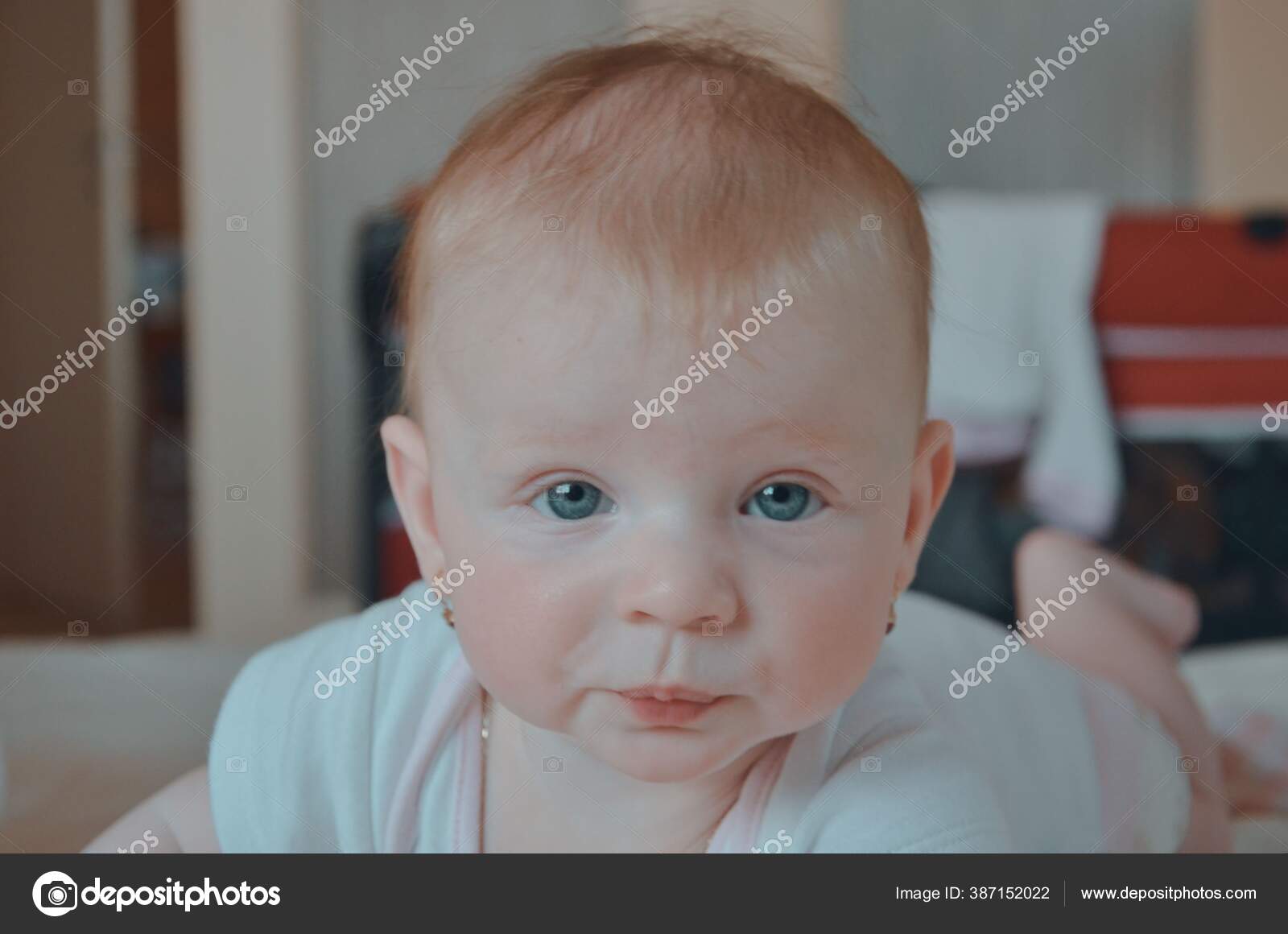 Cute toddler girl lies on the bed smiling. 6 months old baby girl. Portrait of a baby girl on ...