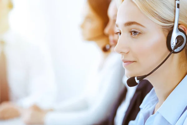 Group of diverse phone operators at work in sunny office. Handsome ...