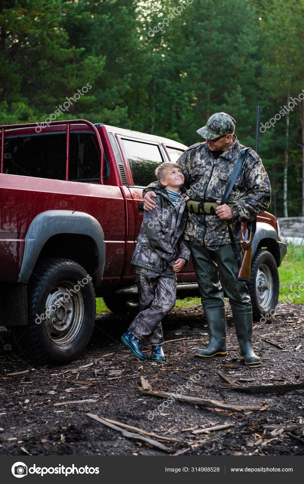 Happy hunter with his son near their pickup truck before hunting in a ...