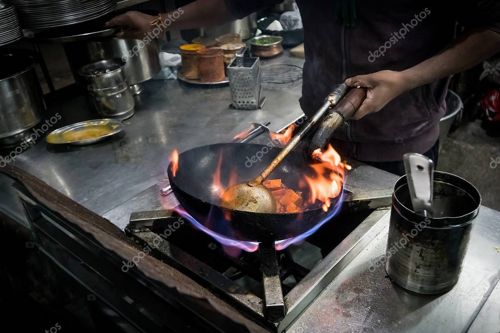 Chef cocinando con fuego con sartén. Chef freír alimentos en una sartén ...