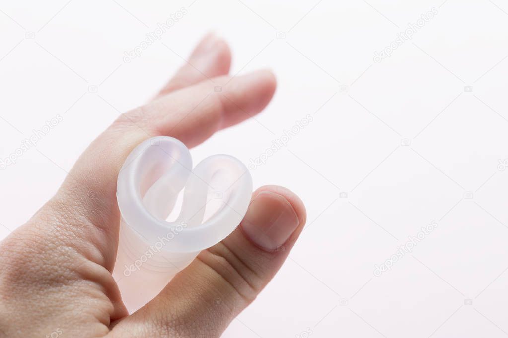 Primer plano de la mano de la mujer plegable copa menstrual que muestra ...
