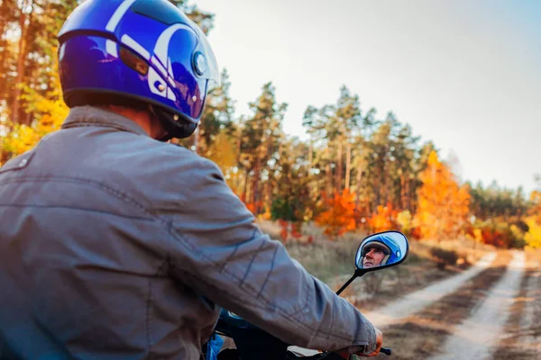 Senior man riding scooter on autumn forest road. Driver in helmet ...