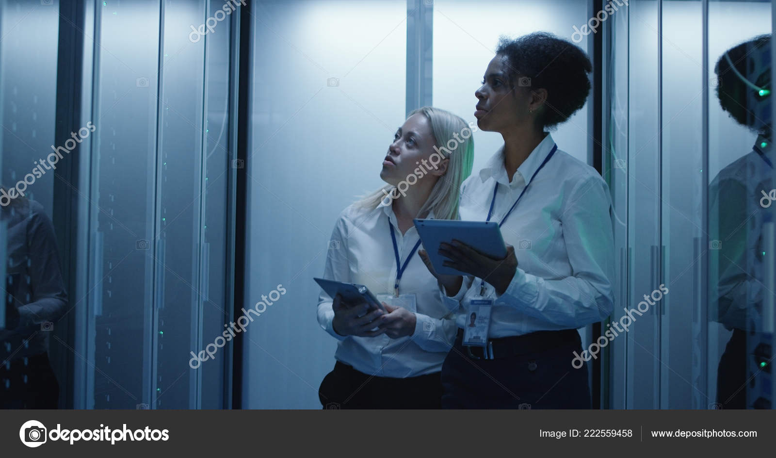 Two women are working in a data center with rows of server racks Stock ...