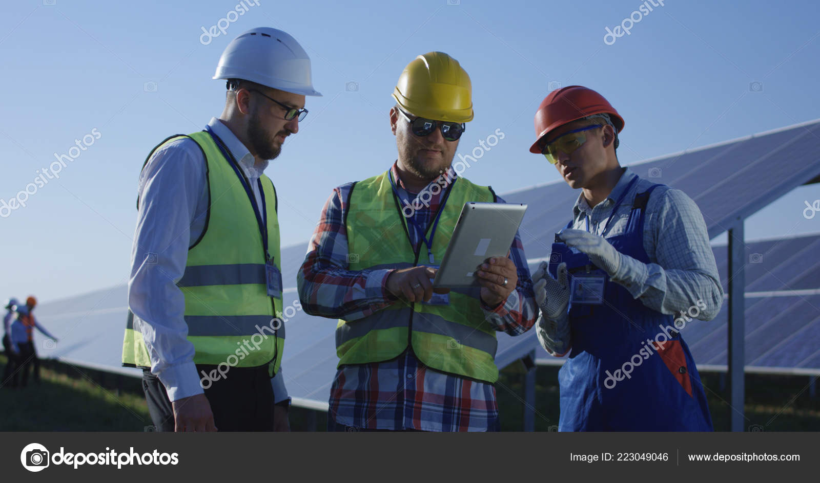 Three electrical workers reviewing documents on a tablet Stock Photo by ...