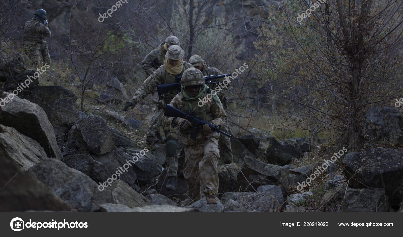 Armed soldiers walking through rocks at dusk Stock Photo by ...