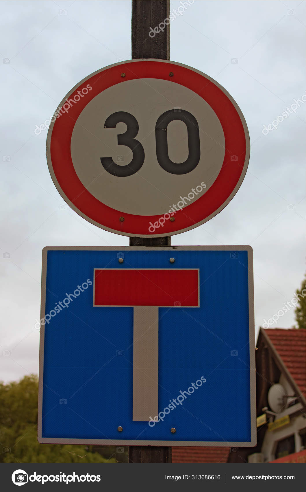 Two road signs on post against cloudy sky represent speed limit and ...