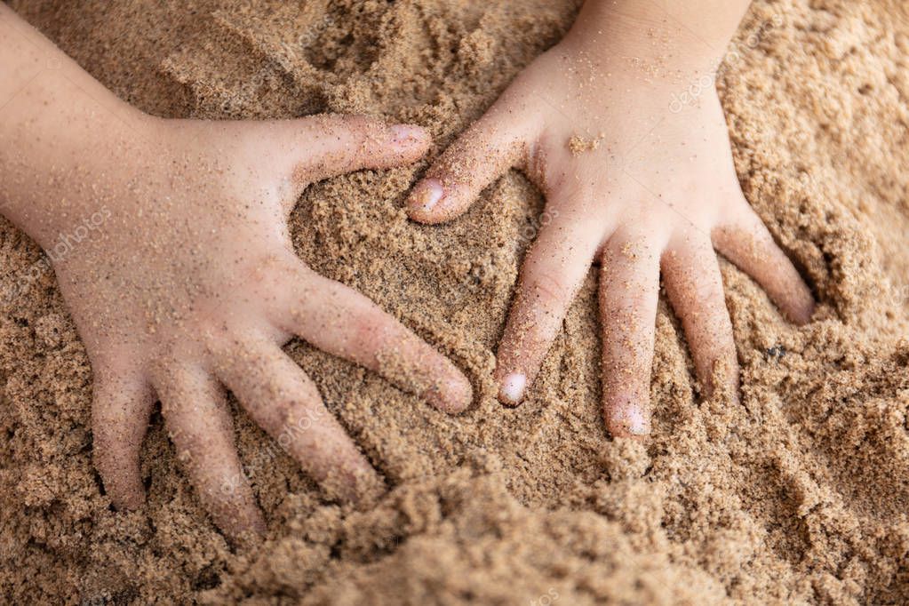 Manos de niños jugando a la arena en la playa 2025