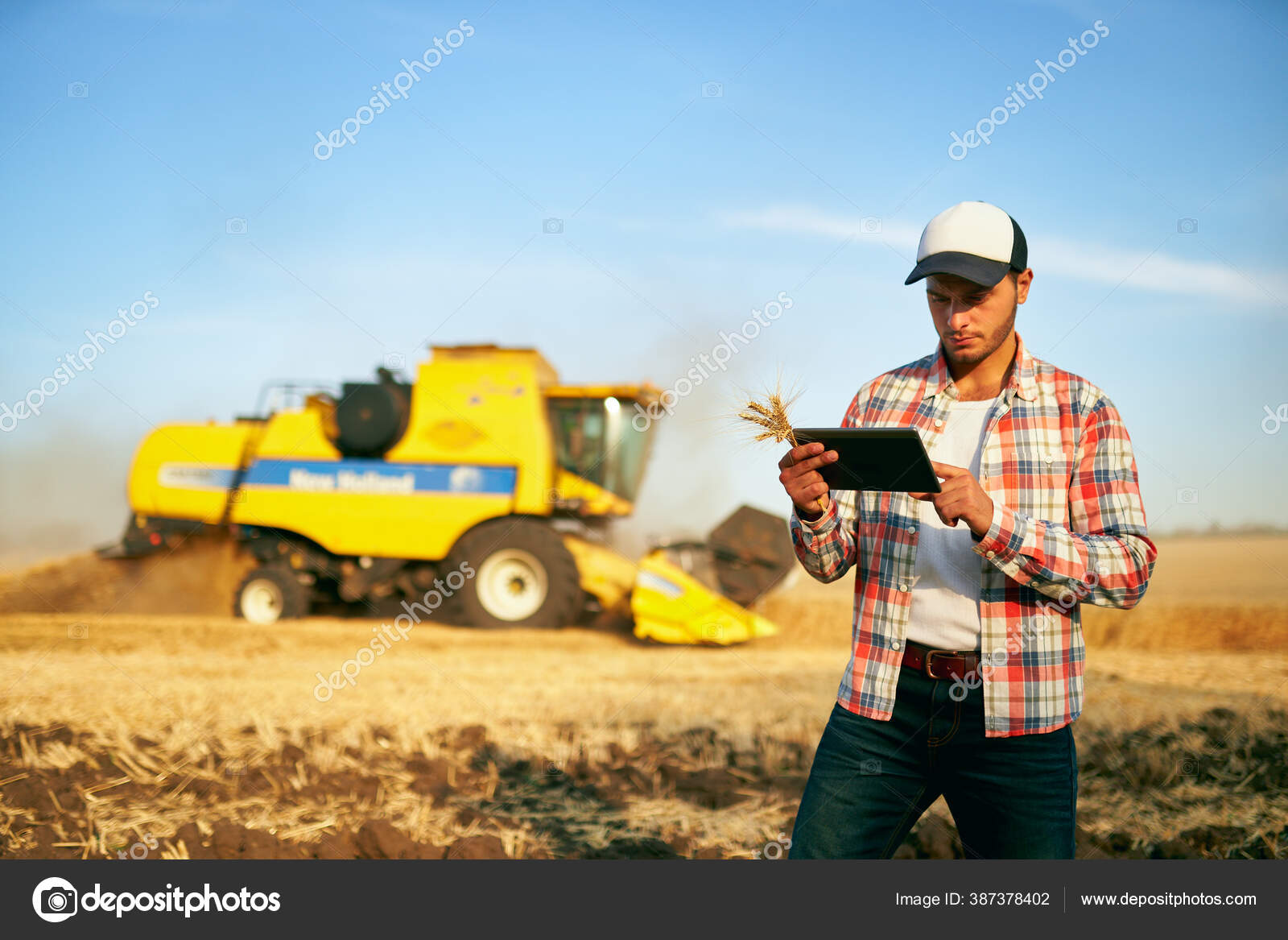 Precision farming. Farmer holding tablet for combine harvester guidance ...