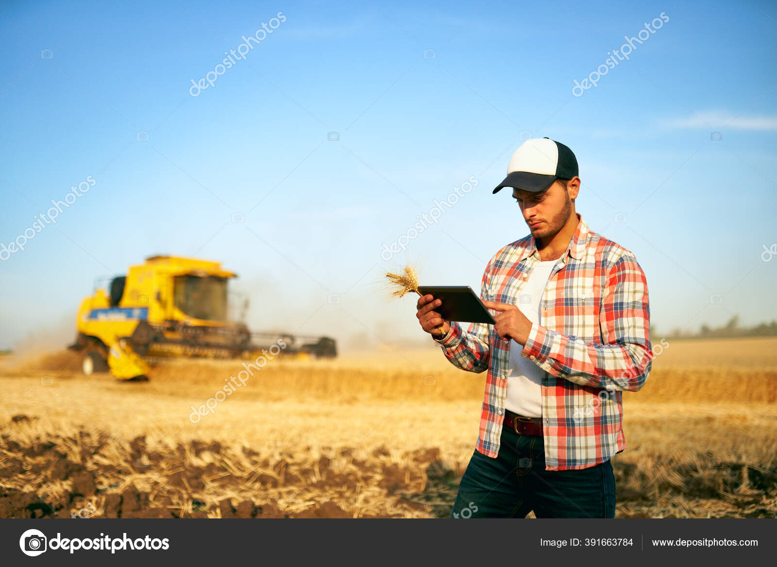 Precision farming. Farmer holding tablet for combine harvester guidance ...