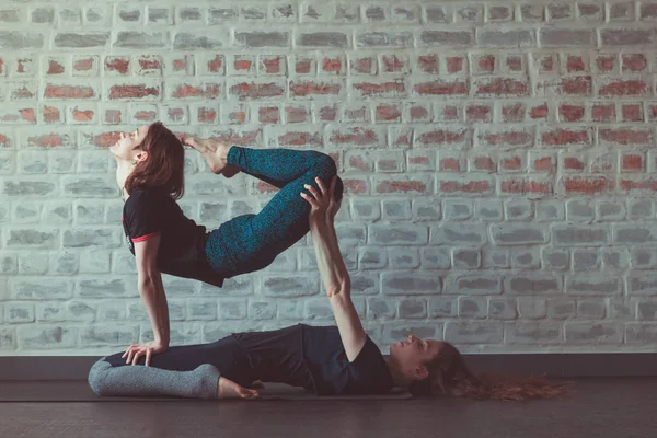 two beautiful caucasian women doing partner yoga in yoga studio ...