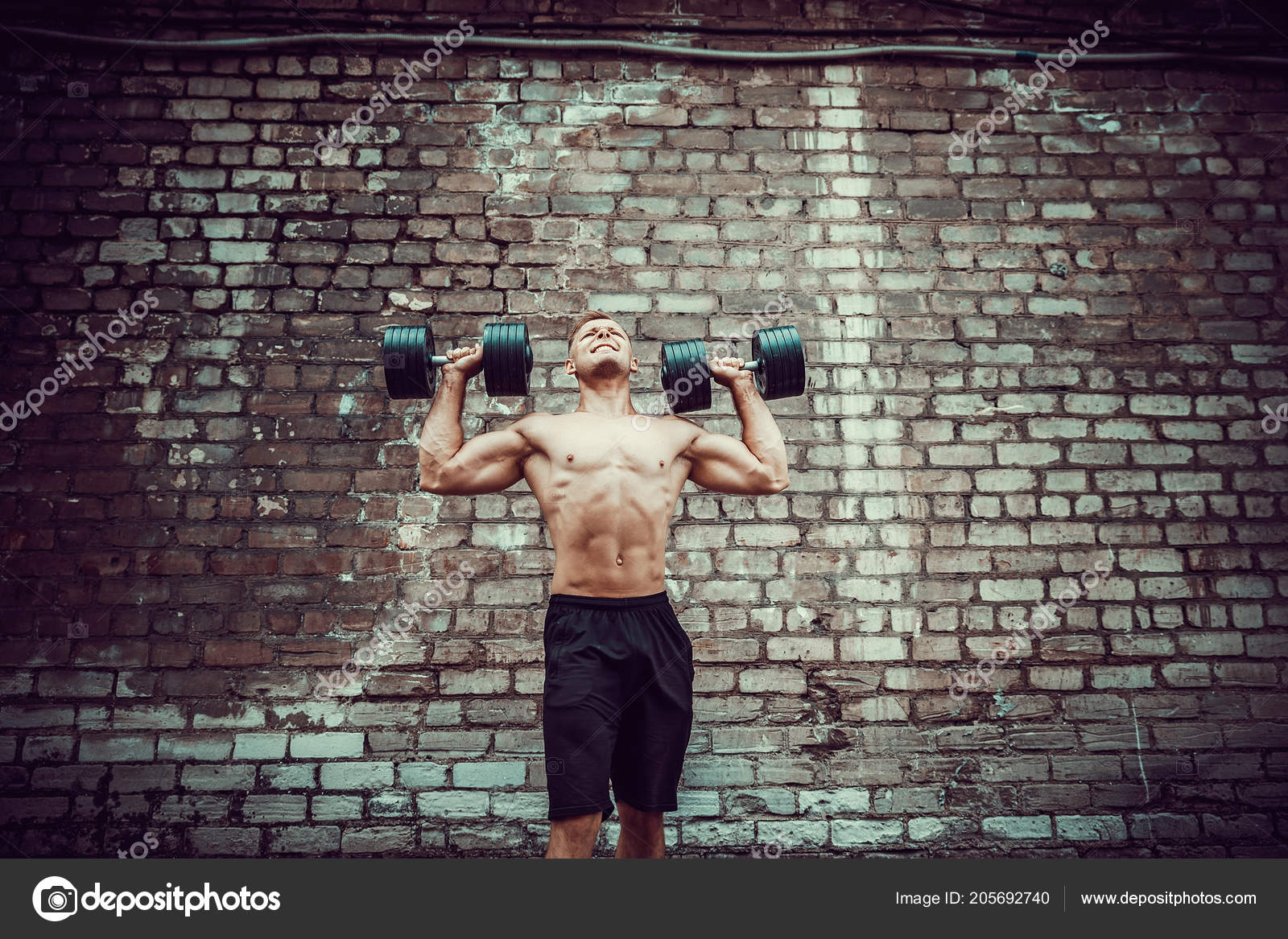 Muscular guy doing exercises with dumbbell against a brick wall — Stock ...