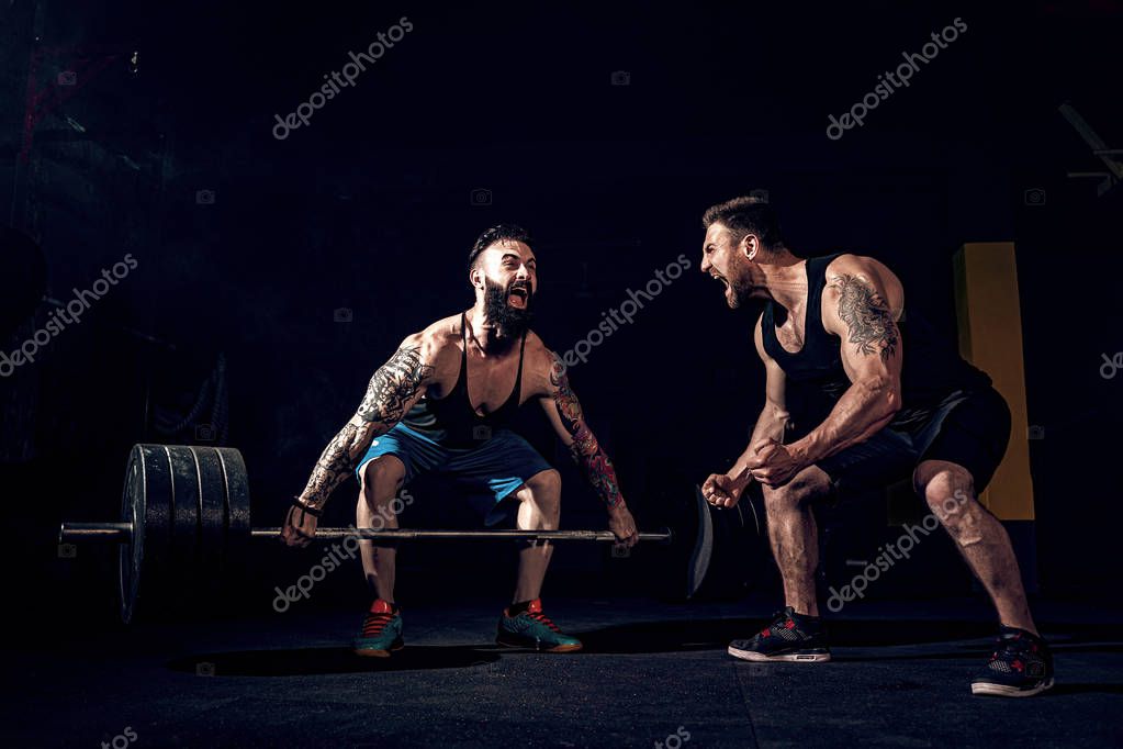 Dos atletas musculosos barbudos tatuados entrenando en el gimnasio 2024