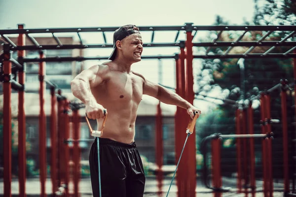 Fitness man exercising with stretching band in outdoor gym. - Stock ...