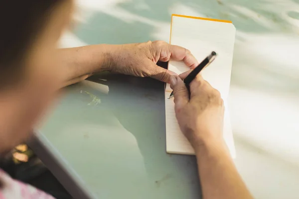 Young person writing on a blank paper with a black pen while sitting in ...