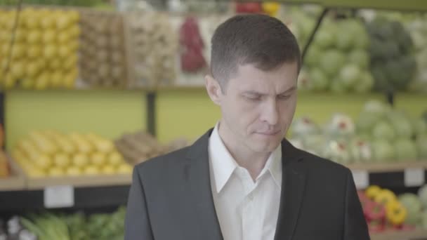 Close-up portrait of serious Caucasian man choosing pear in grocery ...