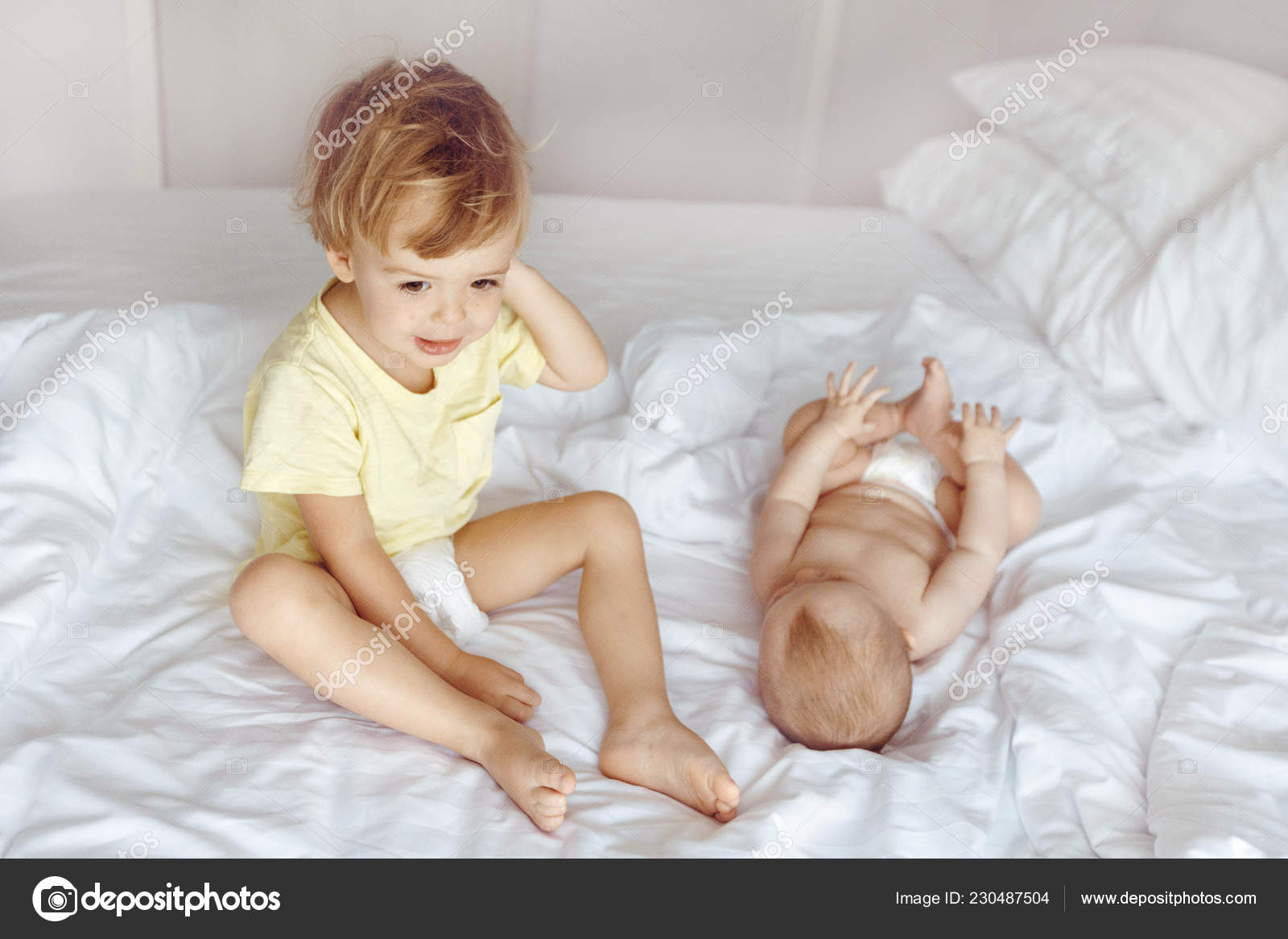 Kid sitting on bed near infant ⬇ Stock Photo, Image by © 371819 #230487504