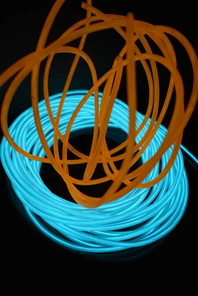 A bright coil of turquoise, sky blue luminous wire with chaotic wires ...