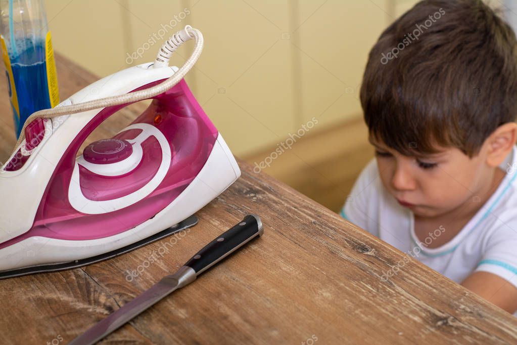 Niño de 3 años de pie y tratando de conseguir un cuchillo de cocina ...