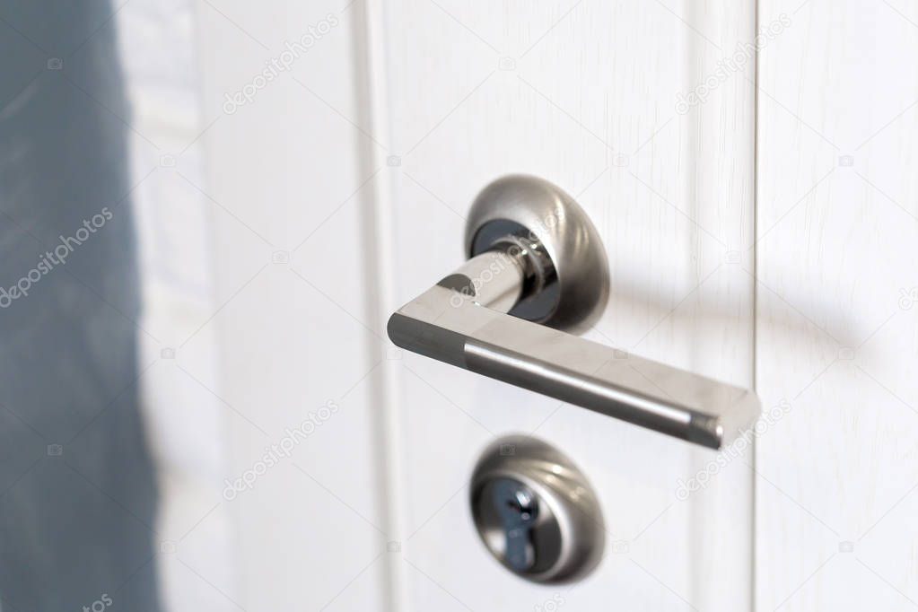 Detalle de una perilla metálica sobre puerta blanca horizontal 2023