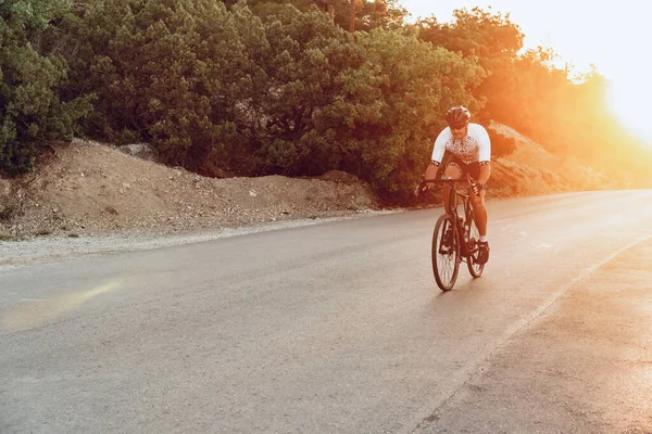Man cyclist pedaling on a road bike outdoors in sun set - Stock Image ...