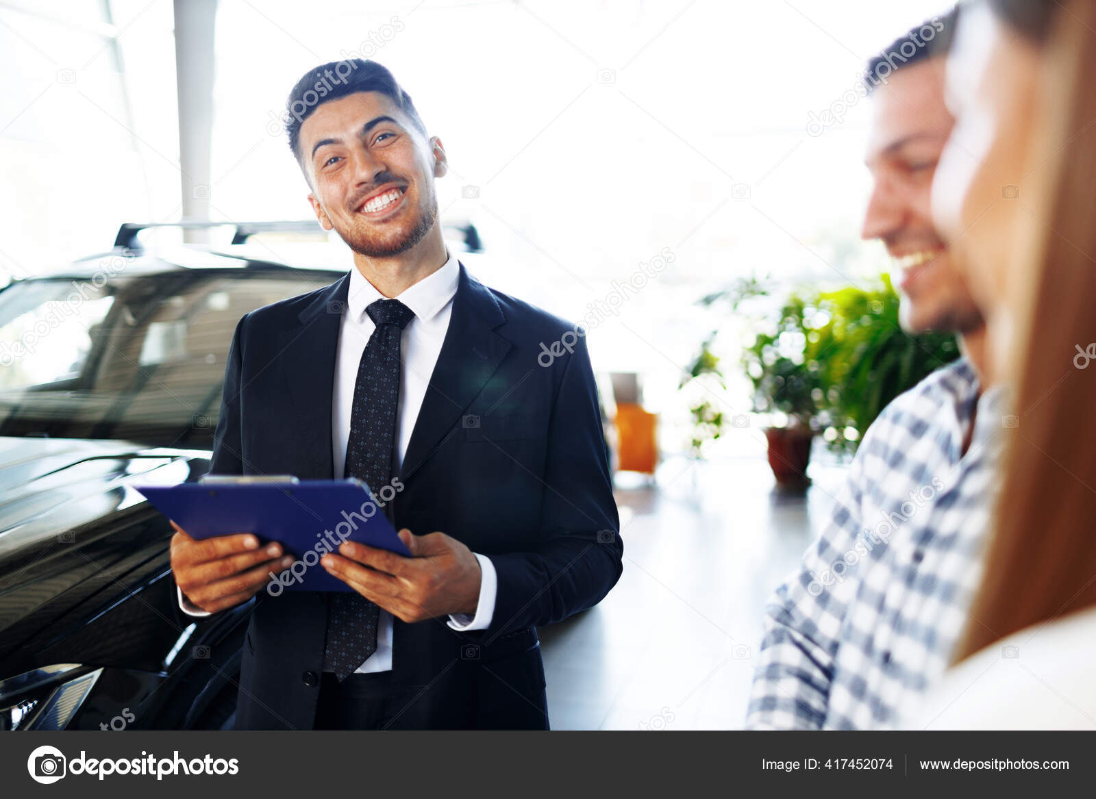 Man car salesman telling about the features of the new car to the ...