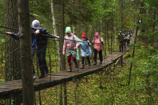 group of people crossing a wooden hanging bridge in the middle of ...