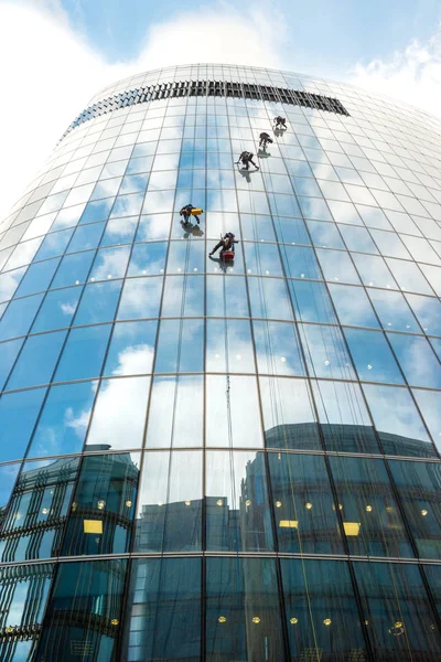 Five window washers work at a height on a high-rise building wit ...