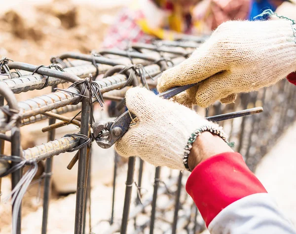 Details of construction worker - hands securing steel bars with wire ...