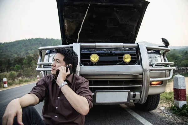 Man try to fix a car engine problem on a local road Chiang mai Thailand ...